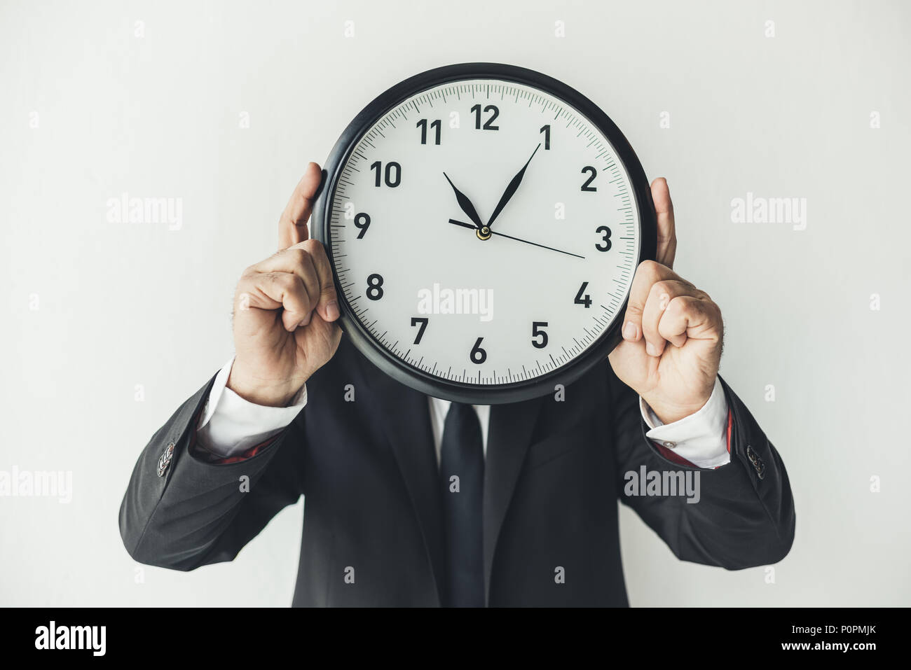 man covering face with clock on light background Stock Photo - Alamy