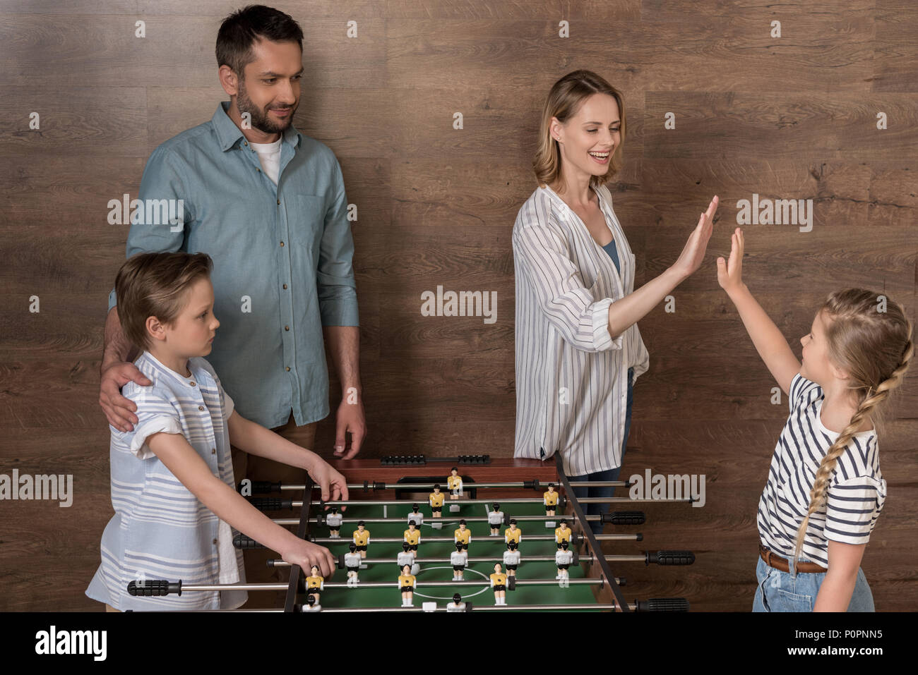 Happy smiling family playing foosball together Stock Photo - Alamy