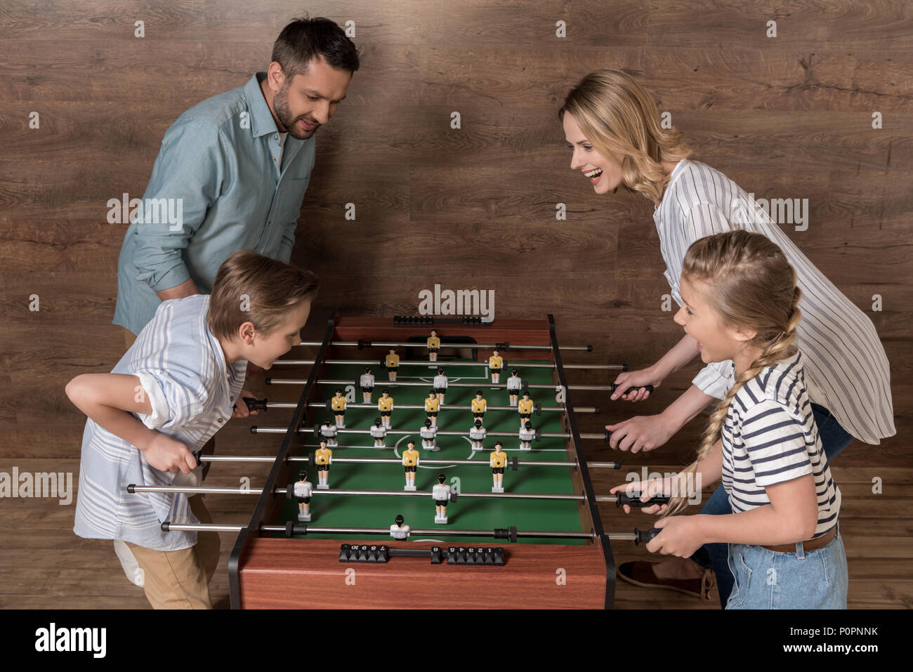 Happy smiling family playing foosball together Stock Photo - Alamy