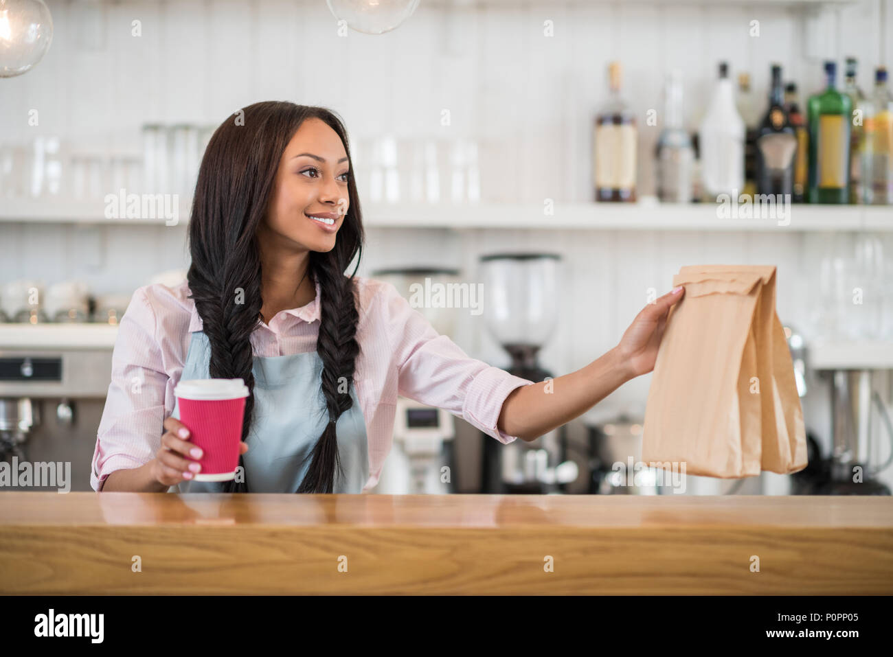 Smiling afro american waitress holding coffee to go and take away food ...