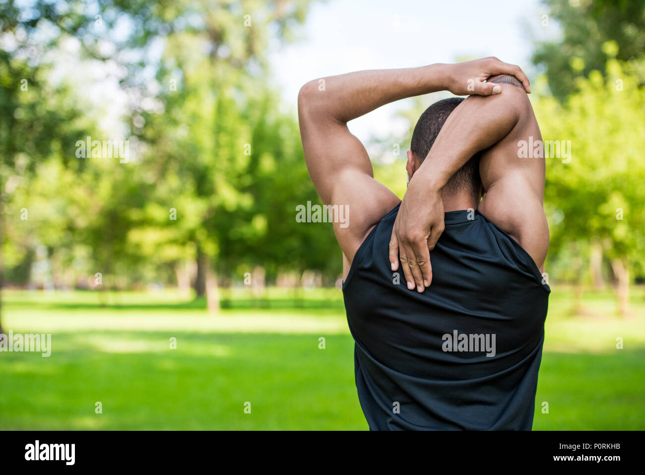 back view of athletic young african american sportsman stretching hands ...