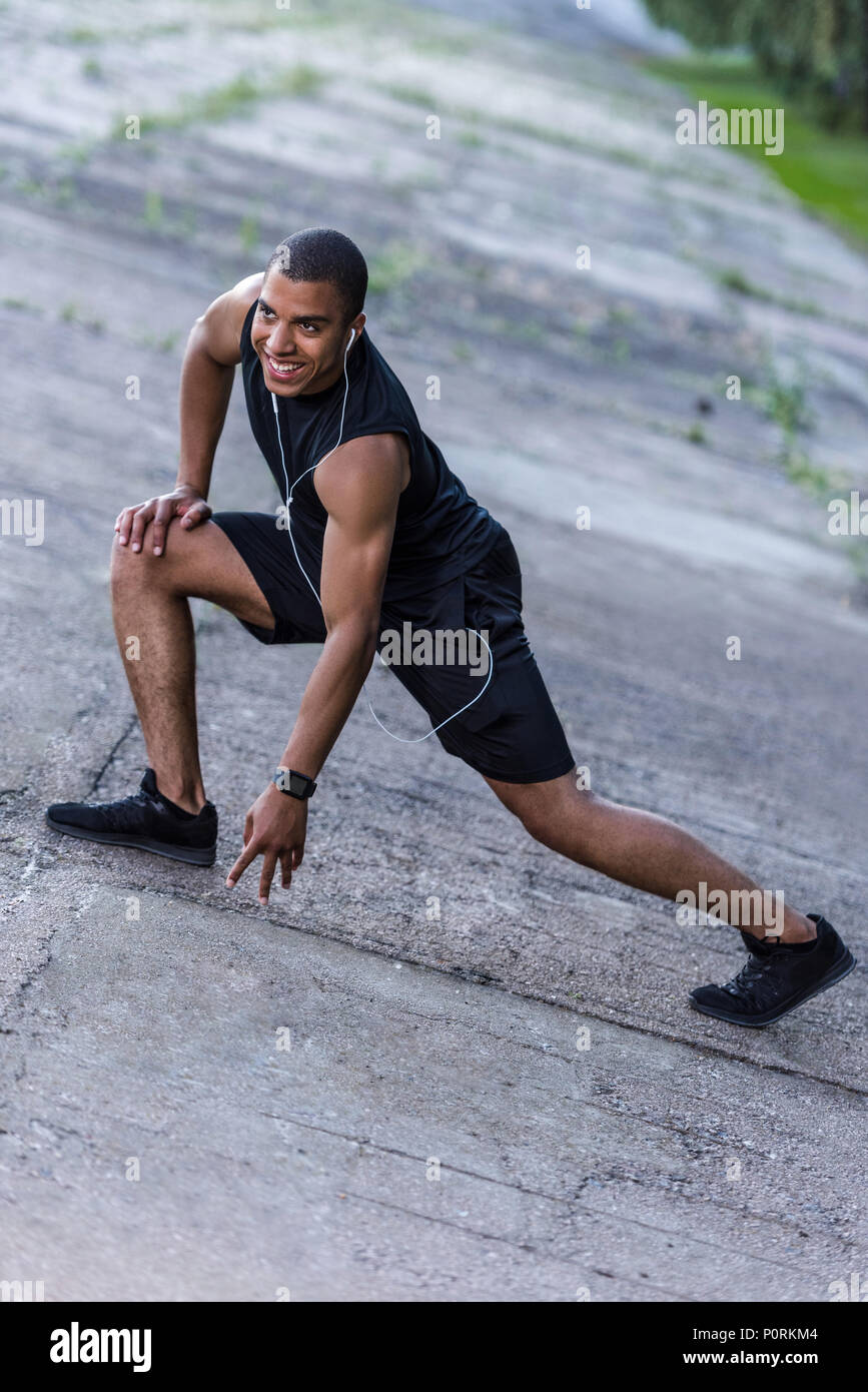 cheerful young african american sportsman ready to run and looking away ...