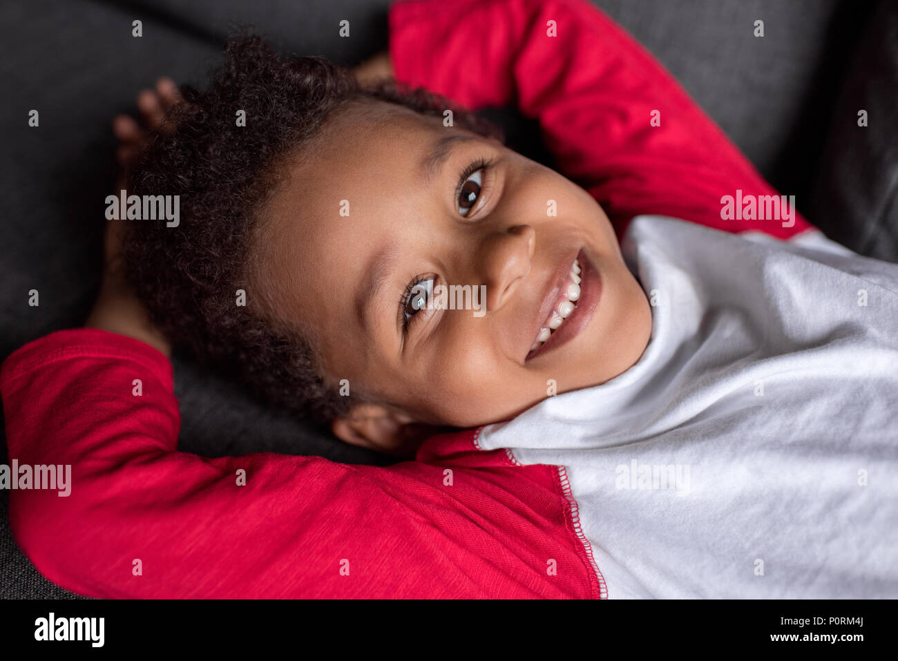 relaxed smiling afro kid laying with hands behind head Stock Photo - Alamy