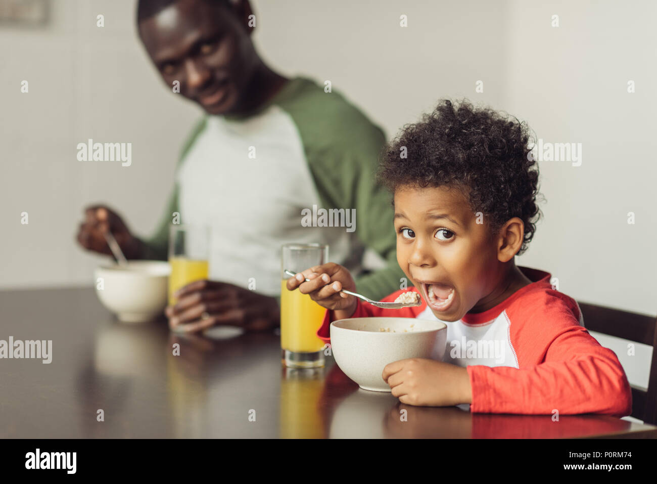 african american father and cute hungry son eating breakfast Stock ...