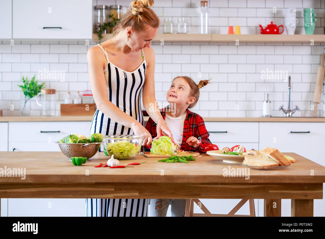 Photo of woman with daughter cooking food in kitchen Stock Photo - Alamy