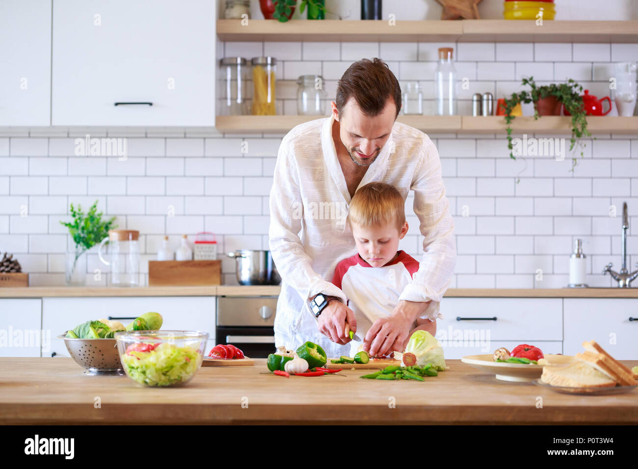 Picture of young father and son cooking at table with vegetables Stock ...