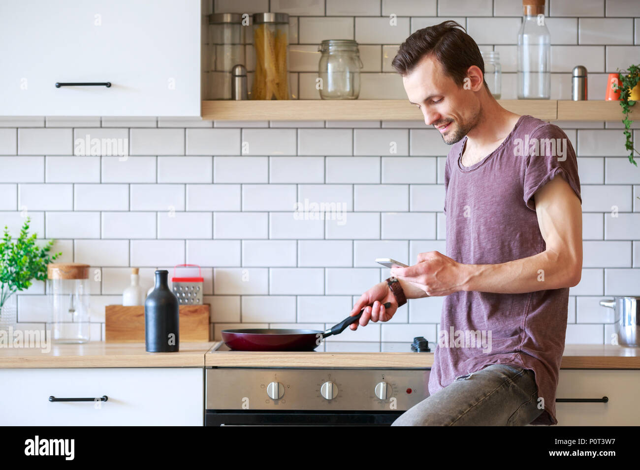 Picture of man with frying pan and phone in hands in kitchen Stock ...