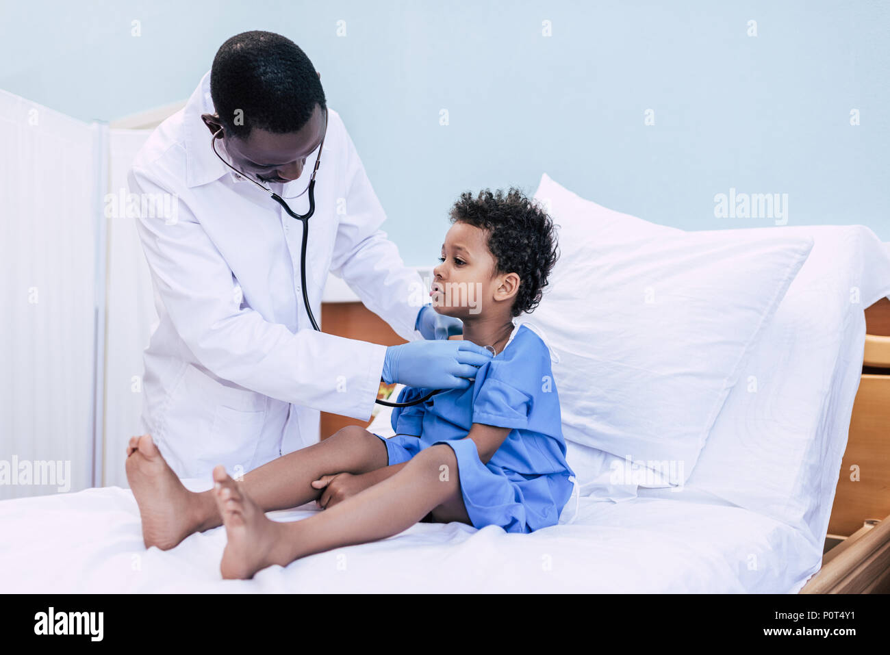 african american doctor with stethoscope checking breathing of little ...
