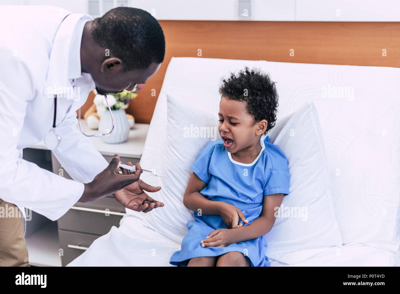 african american doctor making injection to little crying boy in clinic ...
