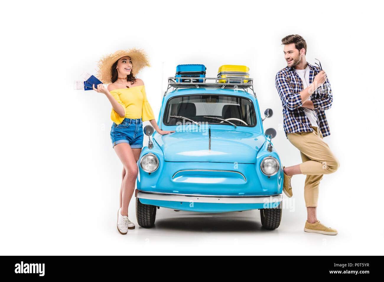 young tourisrs standing by car and holding flying tickets isolated on ...