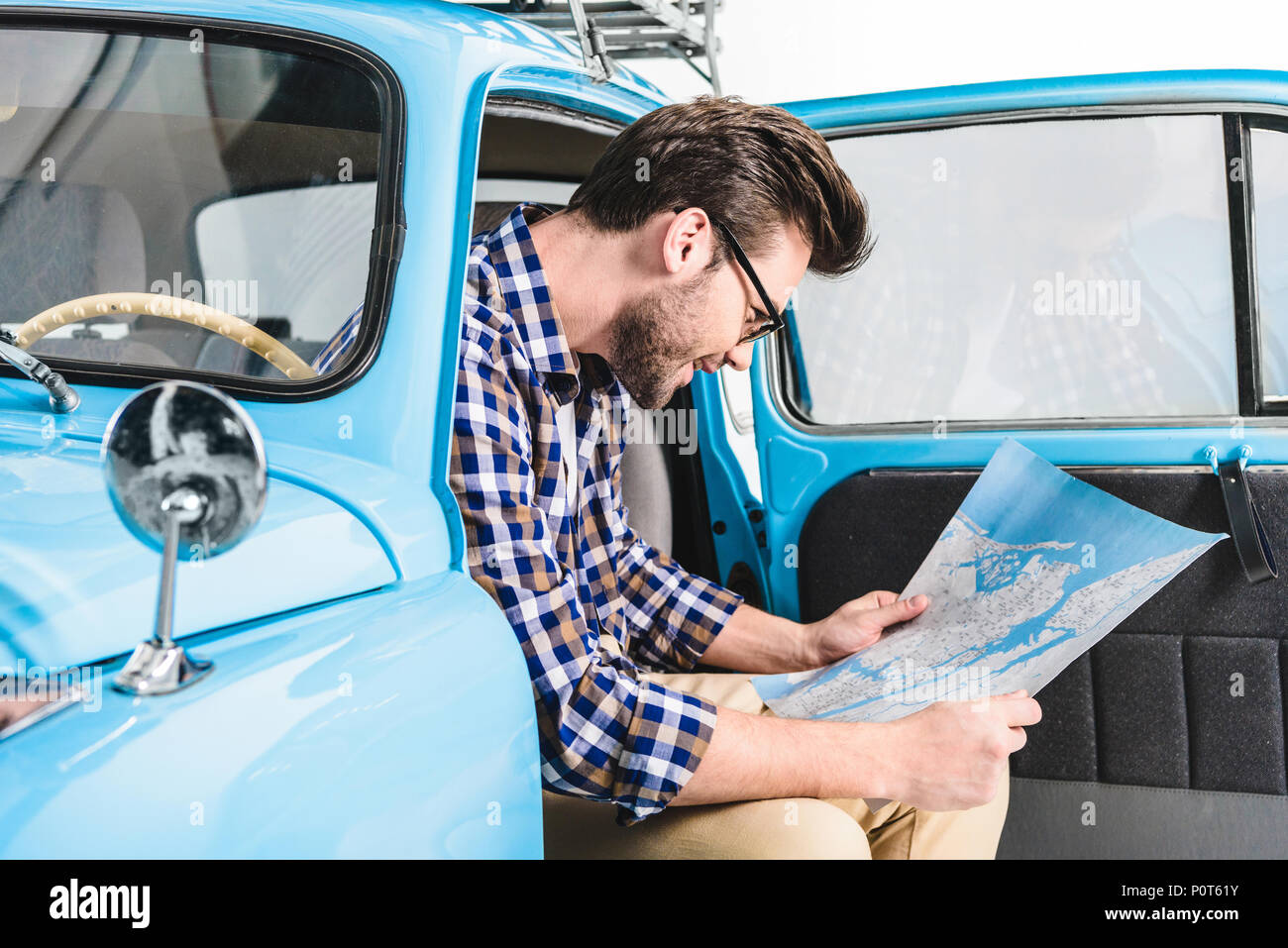 smiling young man sitting in car with map isolated on white Stock Photo ...