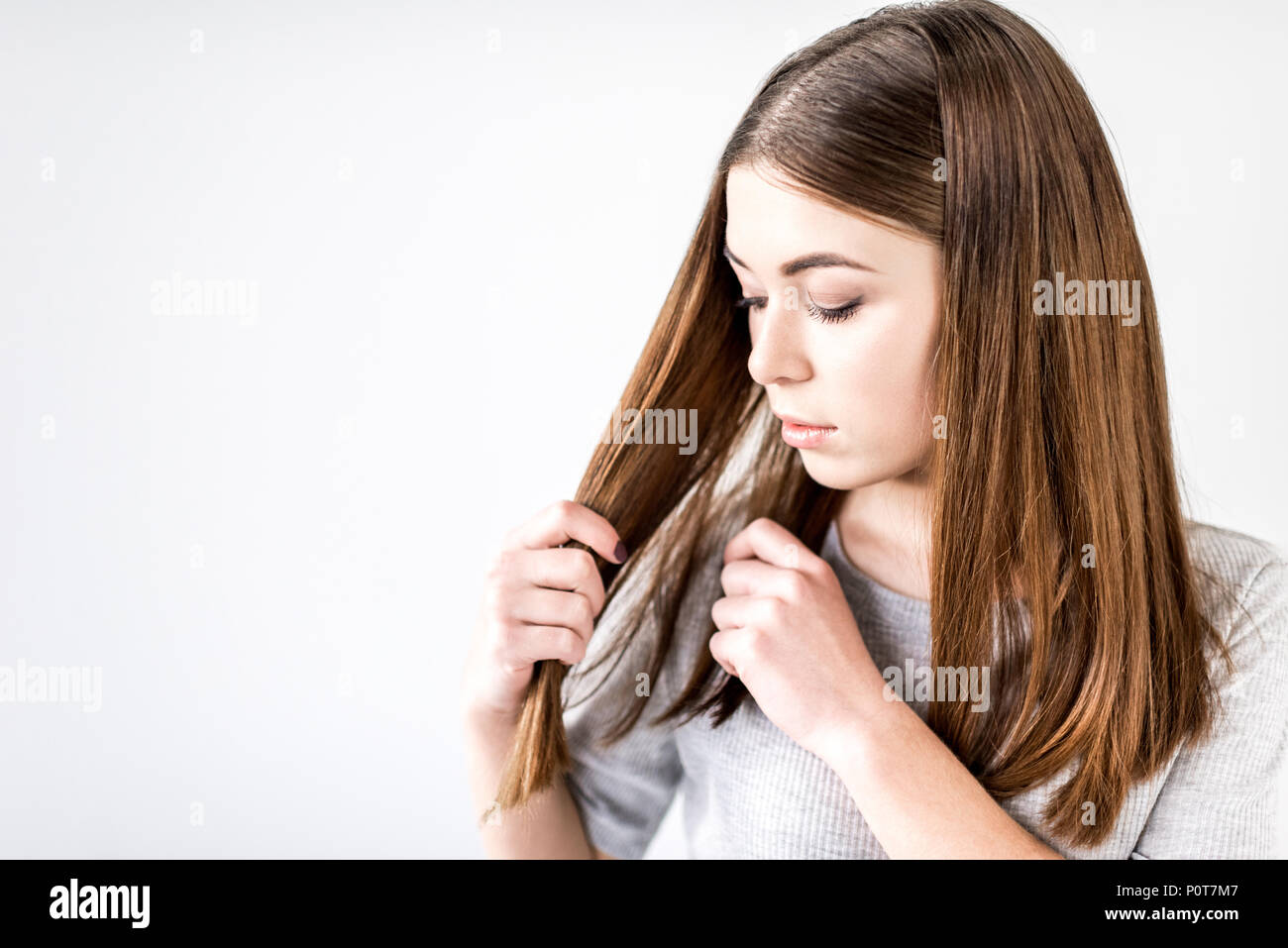 portrait of focused woman checking hair isolated on white Stock Photo ...