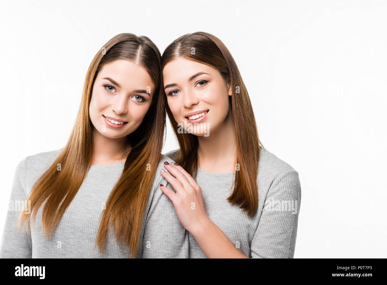 portrait of young smiling twins leaning on each other and looking at ...