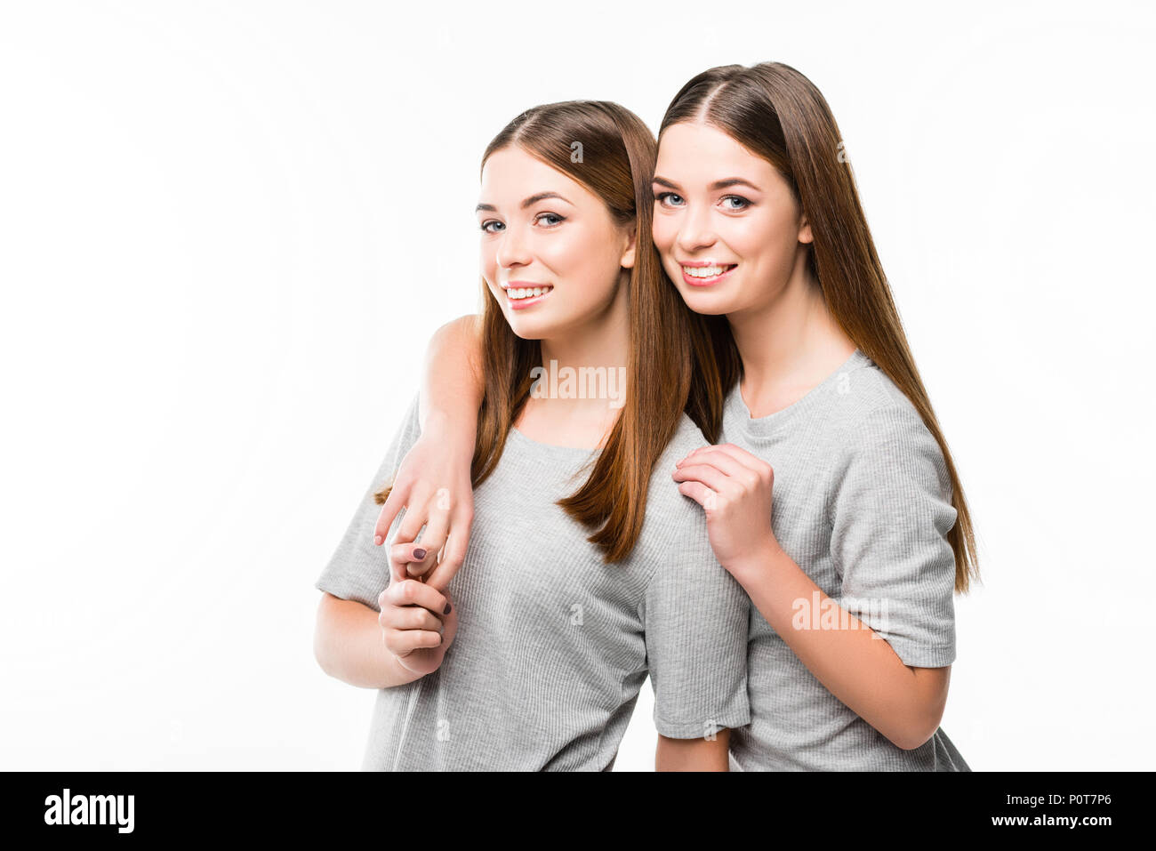 portrait of young smiling twins leaning on each other and looking at ...