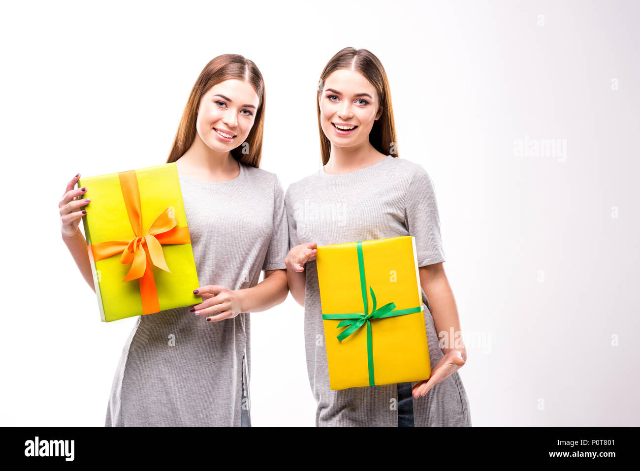 portrait of cheerful twins holding wrapped gifts in hands Stock Photo ...