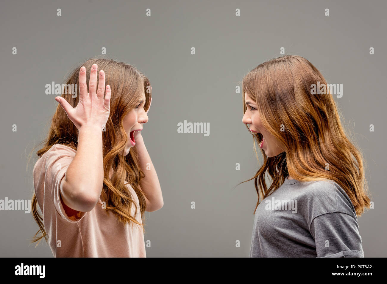 side view of twin sisters screaming at each other isolated on grey ...