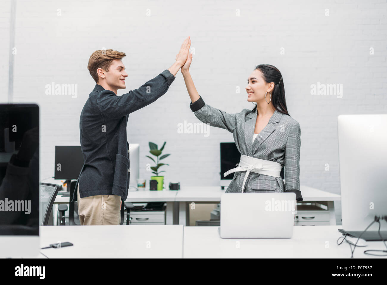 multiethnic business partners giving high five at office Stock Photo ...