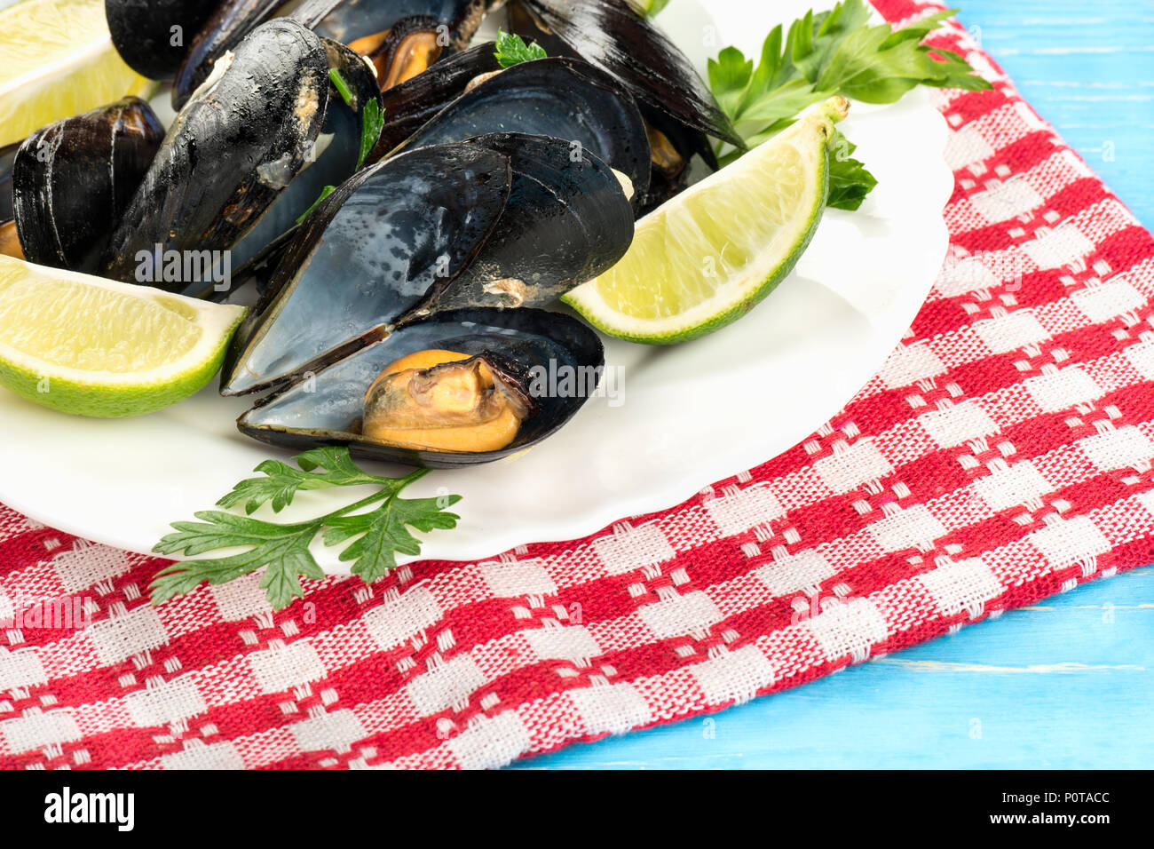 Delicious cooked mussels in the shell on a plate and a towel, close-up ...