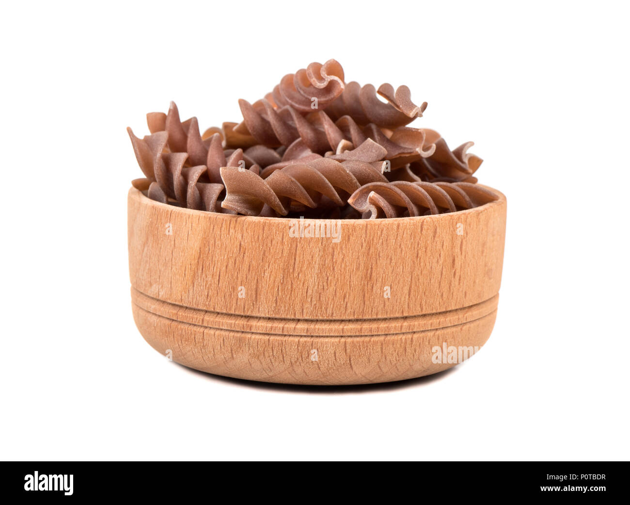 Dark raw pasta fusilli in a small wooden bowl on white background Stock ...