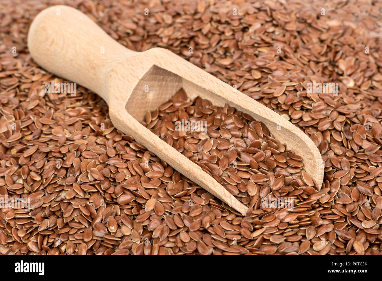 Wooden scoop in a scattered pile of flax seeds close-up Stock Photo - Alamy