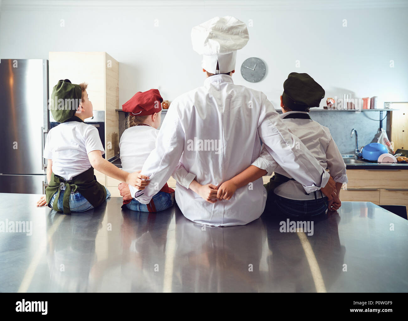 A chef and a group of children in a cook suit in the kitchen Stock ...