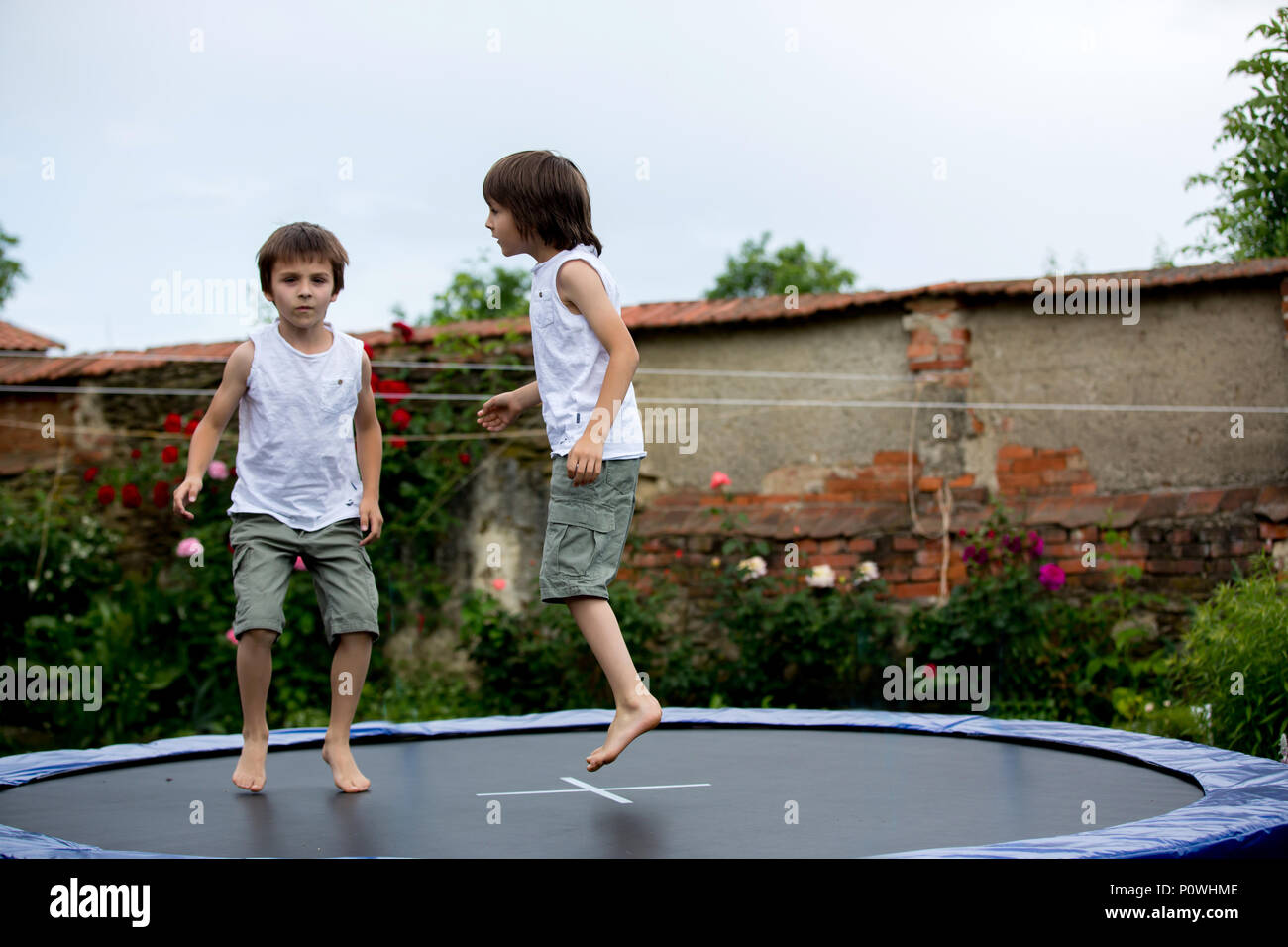 SCute children, brothers, jumping on a trampoline in garden, summertime ...