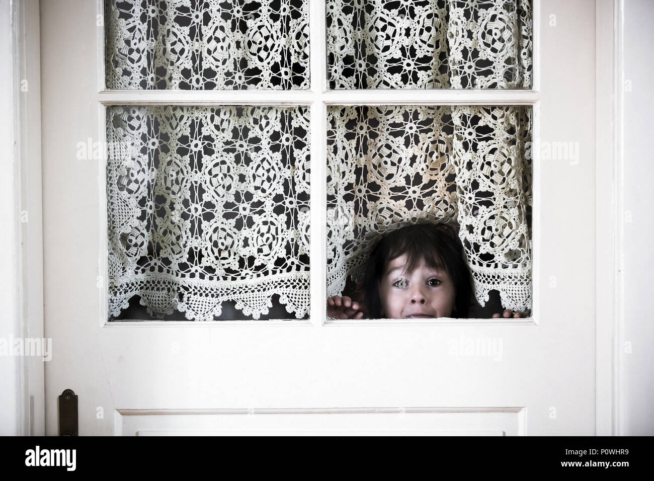 Little preschool boy, child, looking out scared through a door with ...