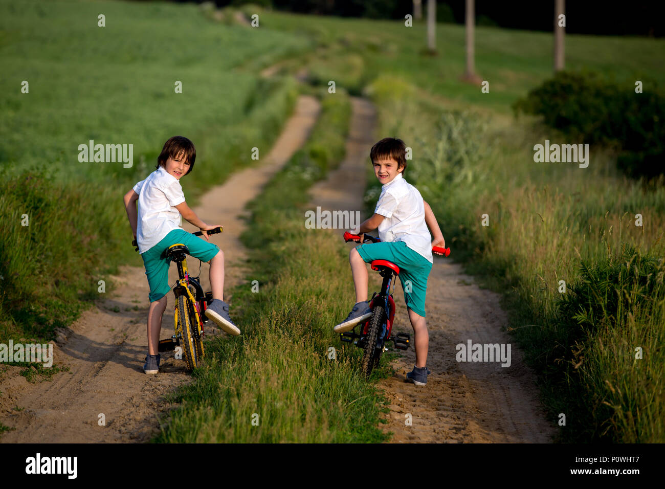 Sporty children, boy brothers, riding bikes on a rural landscape ...