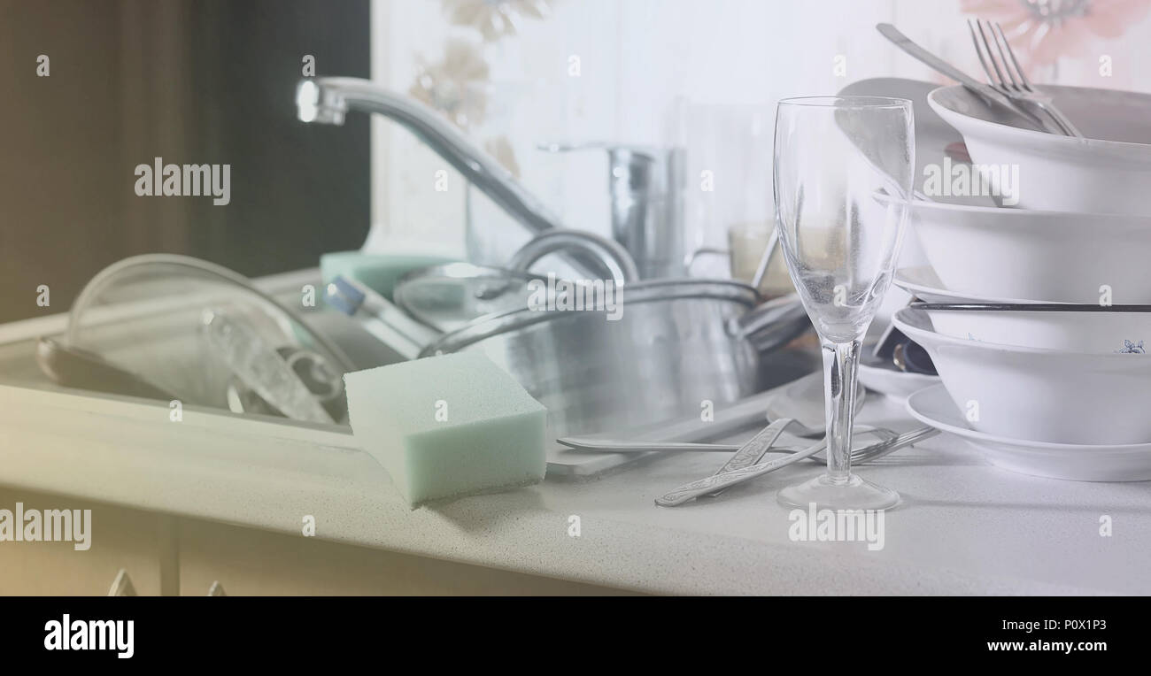 A huge pile of unwashed dishes in the kitchen sink and on the ...