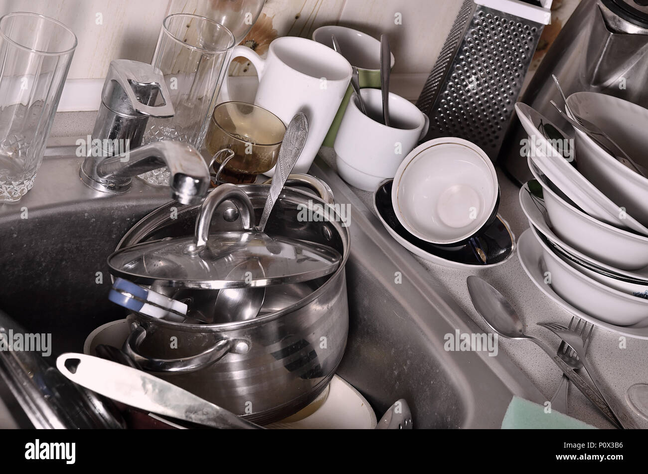 A huge pile of unwashed dishes in the kitchen sink and on the ...