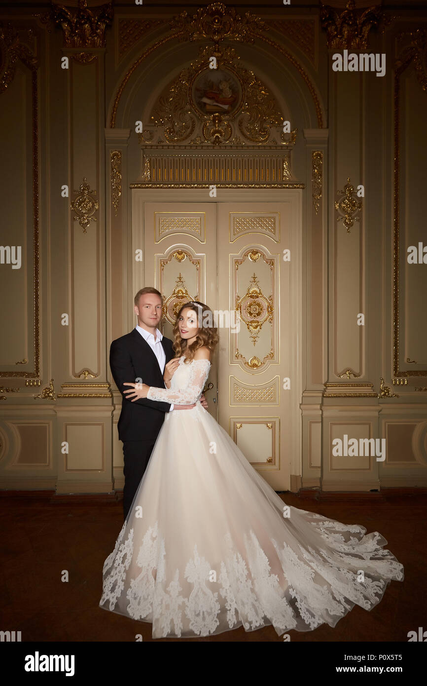 Charming wedding couple in interior in Baroque style is hugging each ...