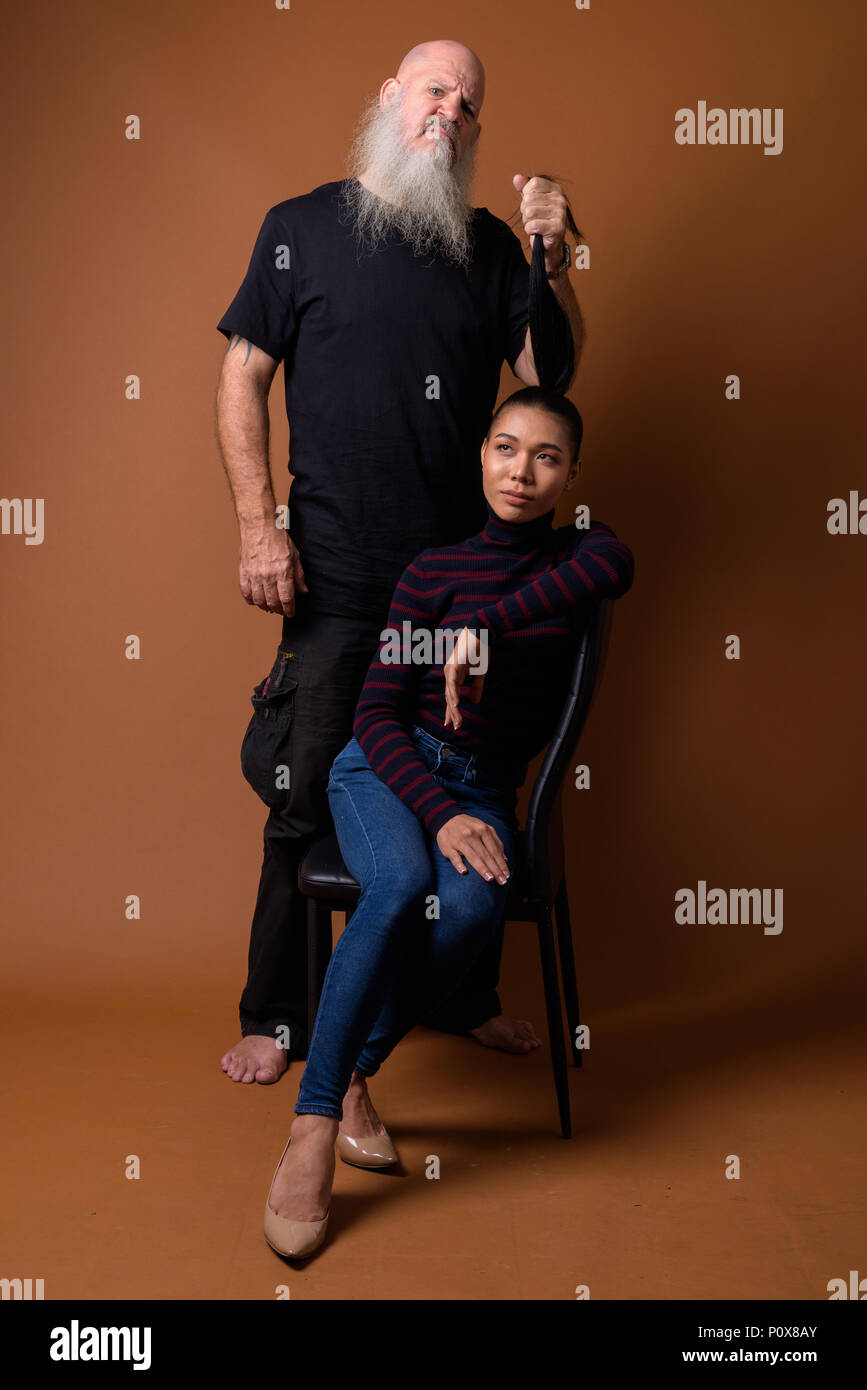 Mature bearded bald man with young Asian transgender woman Stock Photo ...