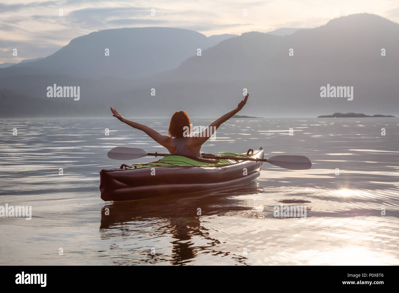 Woman on a kayak is enjoying the beautiful Canadian Mountain Landscape ...