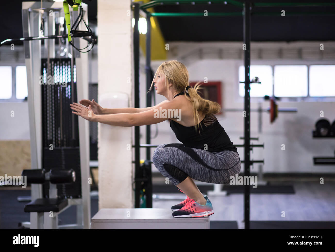 young athletic woman training jumping on fit box at cross fitness gym ...