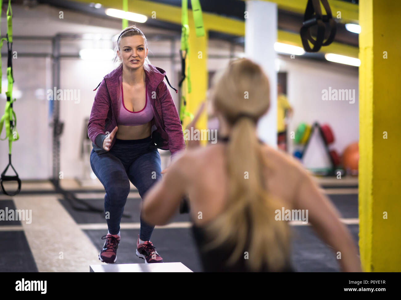 group of young healthy athletic people training jumping on fit box at ...