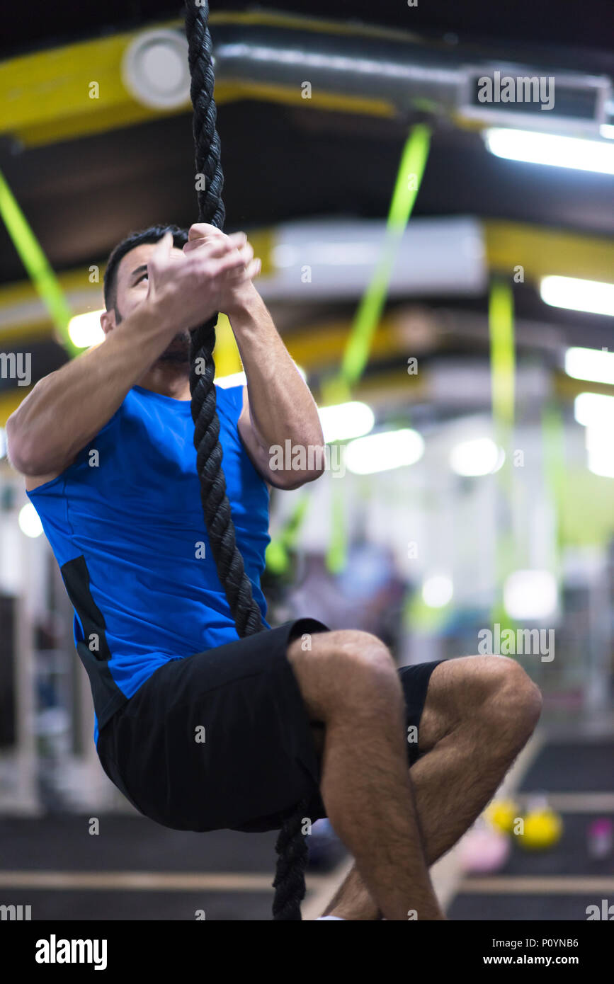 young muscular man doing rope climbing in cross fitness gym Stock Photo ...