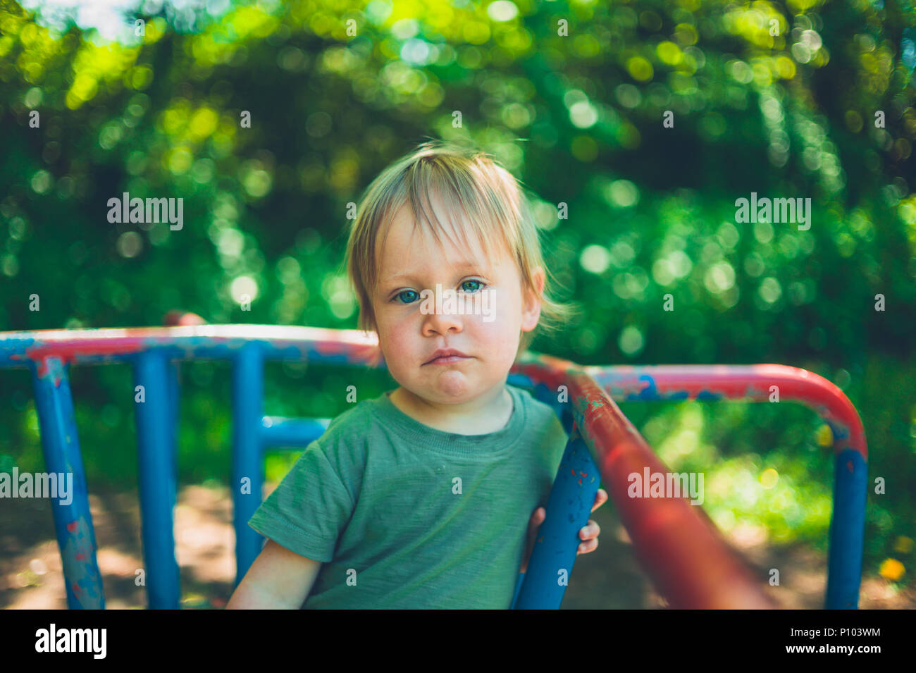 A cute little boy is sitting on a merry-go-round in the park Stock ...