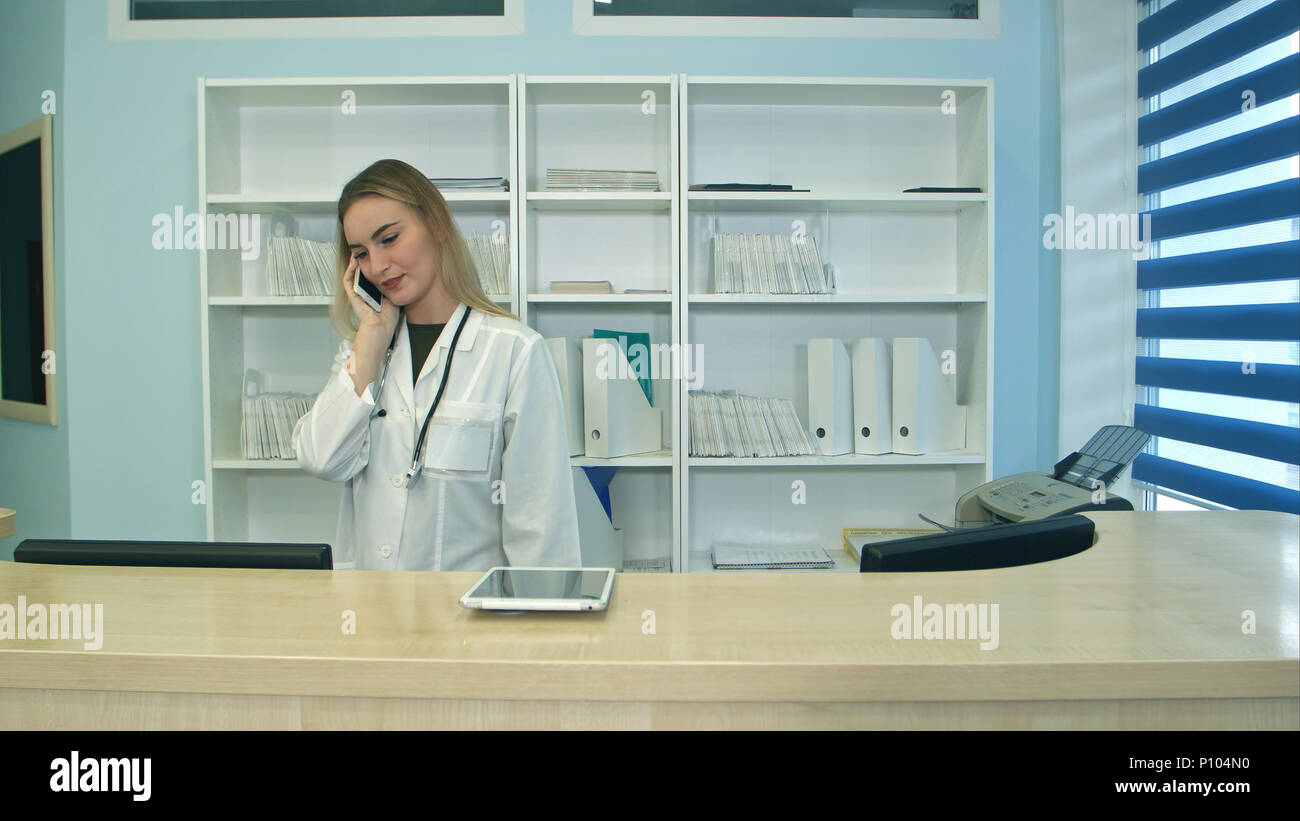 Female nurse at hospital reception answering phone calls and scheduling ...