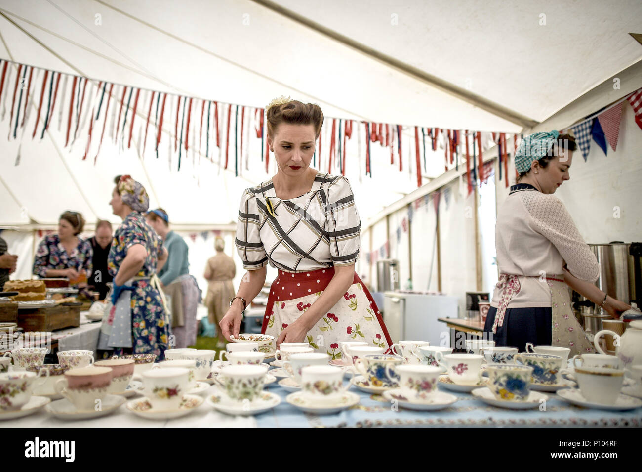 Tea ladies dressed in 1940's period clothes serve tea from china cups ...