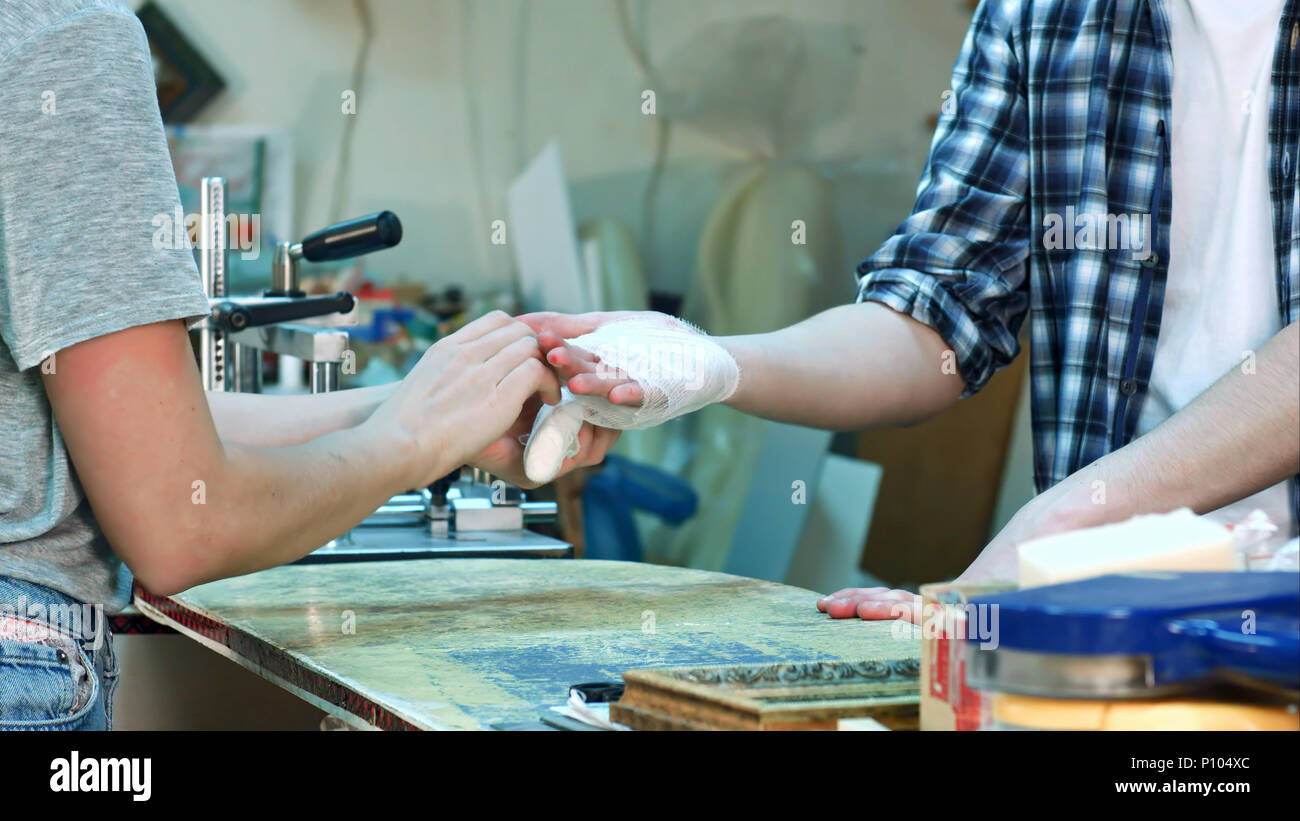 Female hands carefully bandaging worker injured hand after accident ...