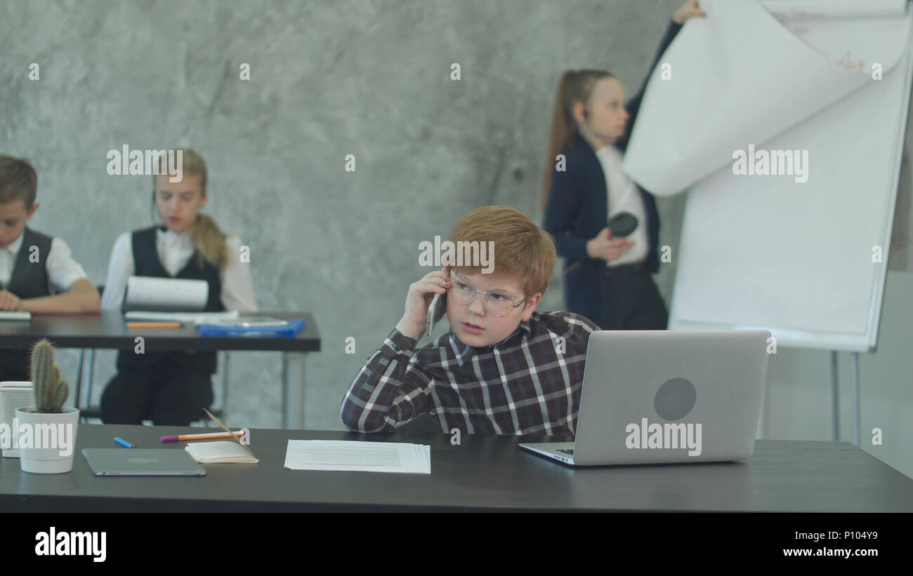 Child boss on the phone working on laptop Stock Photo - Alamy
