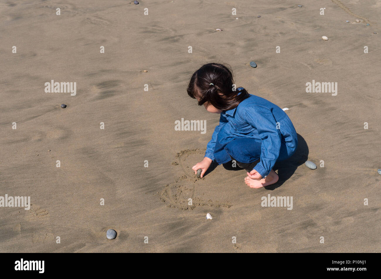 girl drawing in sand Stock Photo - Alamy
