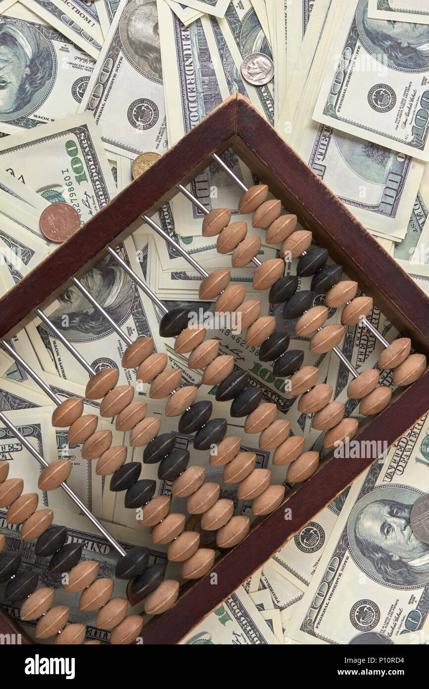 Old accounting wooden abacus on pile of money. US dollars and coins ...