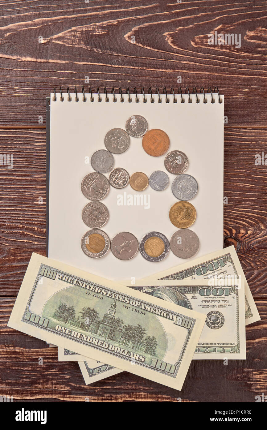 Coins and dollars with notepad. Coin house. Wooden desk background ...