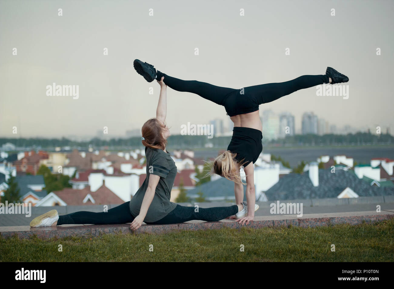Two young female gymnasts doing acrobatics elements with cityscape on ...