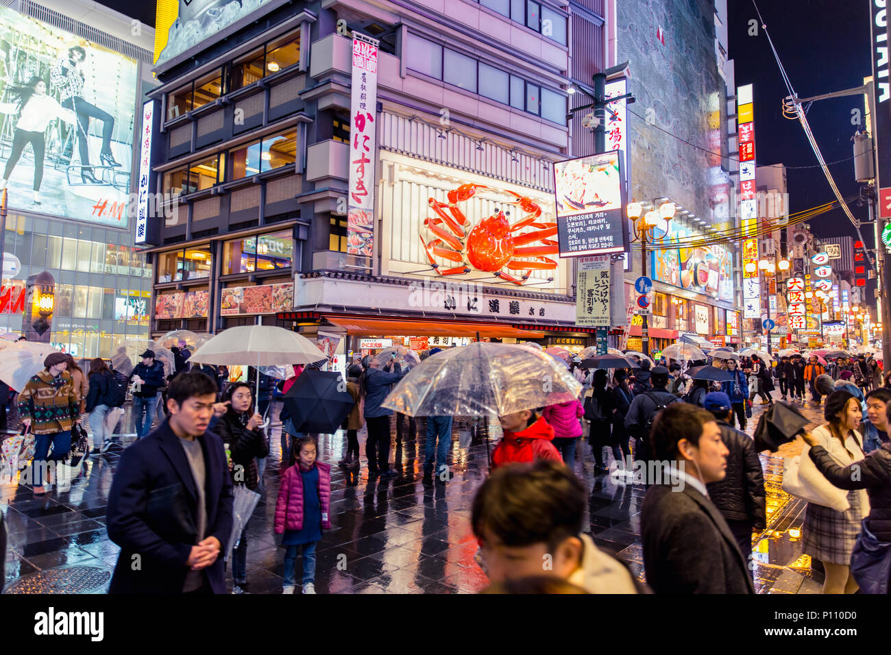 crowded people walking in colorful night raining street in Dotonbori ...