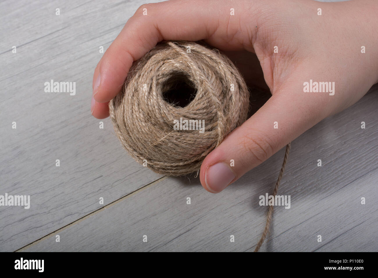 Spool of brown string in hand on white background Stock Photo - Alamy