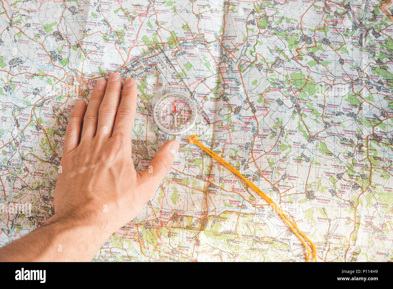 Man holding a compass above a map trying to find a way Stock Photo - Alamy