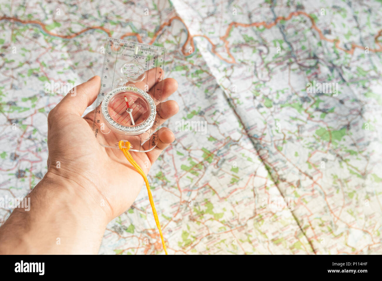 Man holding a compass above a map trying to find a way Stock Photo - Alamy
