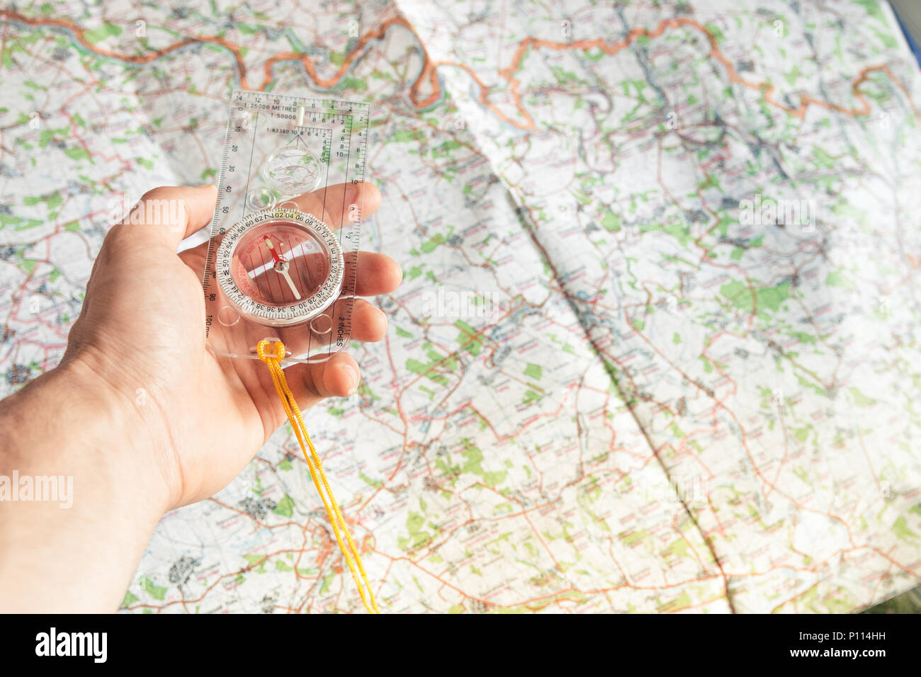 Man holding a compass in one hand above a map trying to find a way ...
